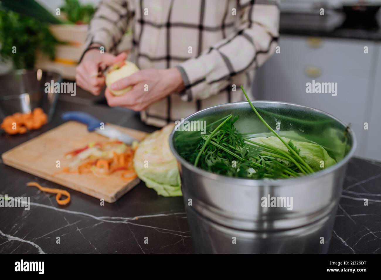 Woman throwing vegetable cuttings in a compost bucket in kitchen Stock ...