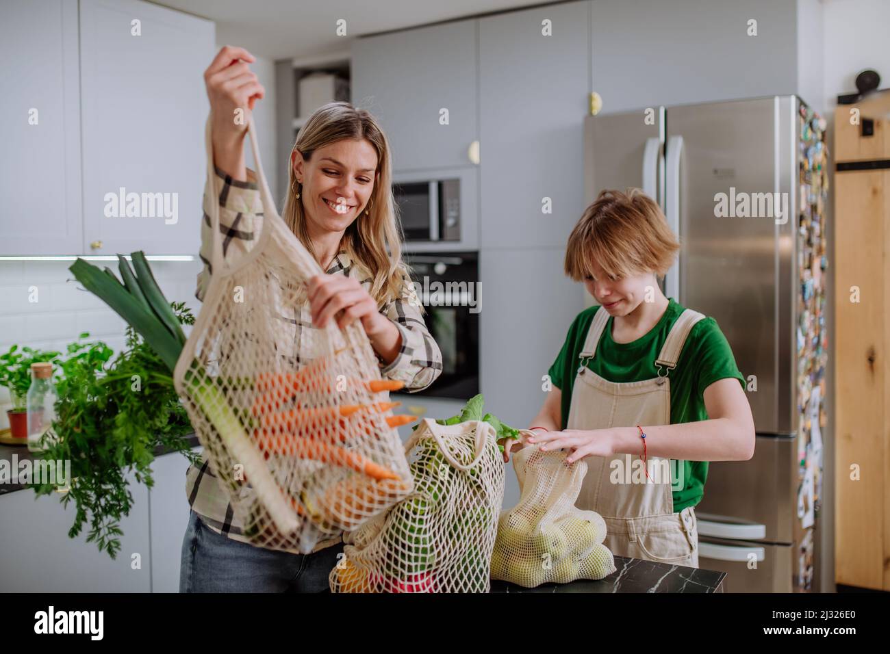 Mother unpacking local food in zero waste packaging from bag with help ...