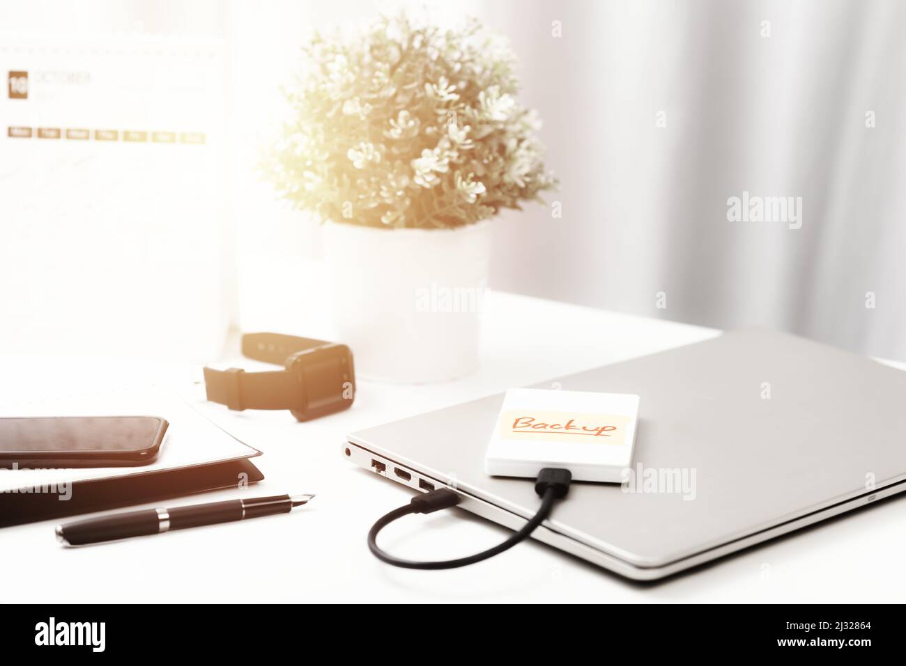 Closeup external hard drive with a tape labeled backup on white desktop ...