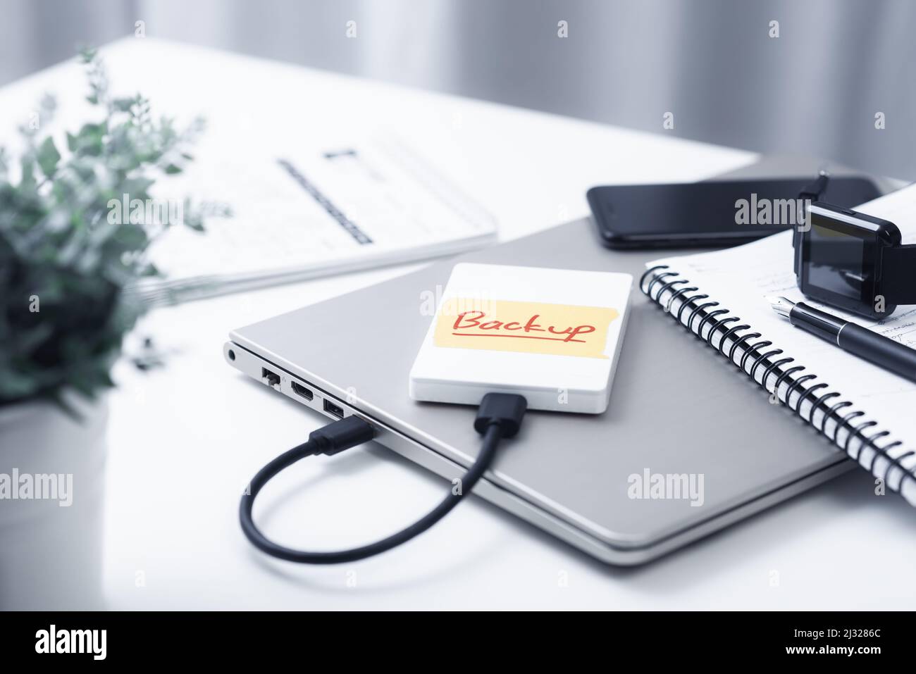 Closeup external hard drive with a tape labeled backup on white desktop ...