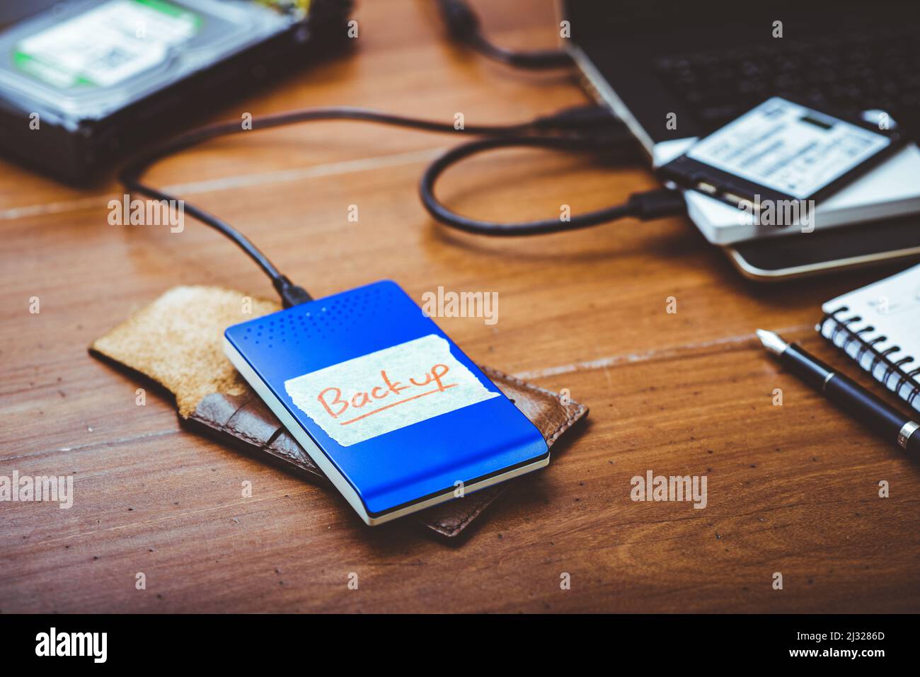 Closeup external hard drive with a tape labeled backup on wooden ...