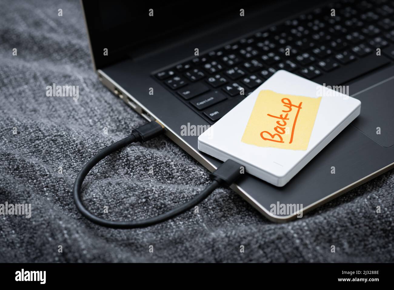 Closeup external hard drive with a tape labeled backup. Working with ...