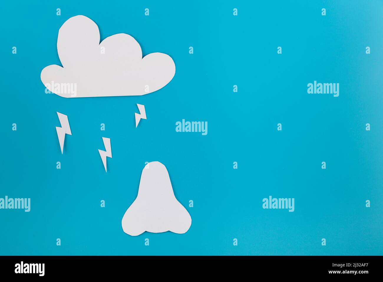 Paper silhouette of a cloud, lightning and nose on a blue background ...