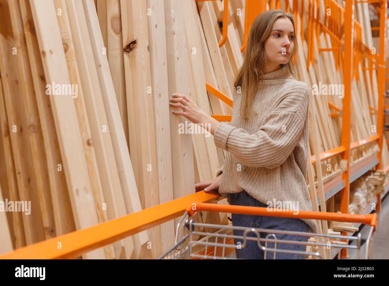 Woman choosing wooden plank in hardware store. Building materials for ...