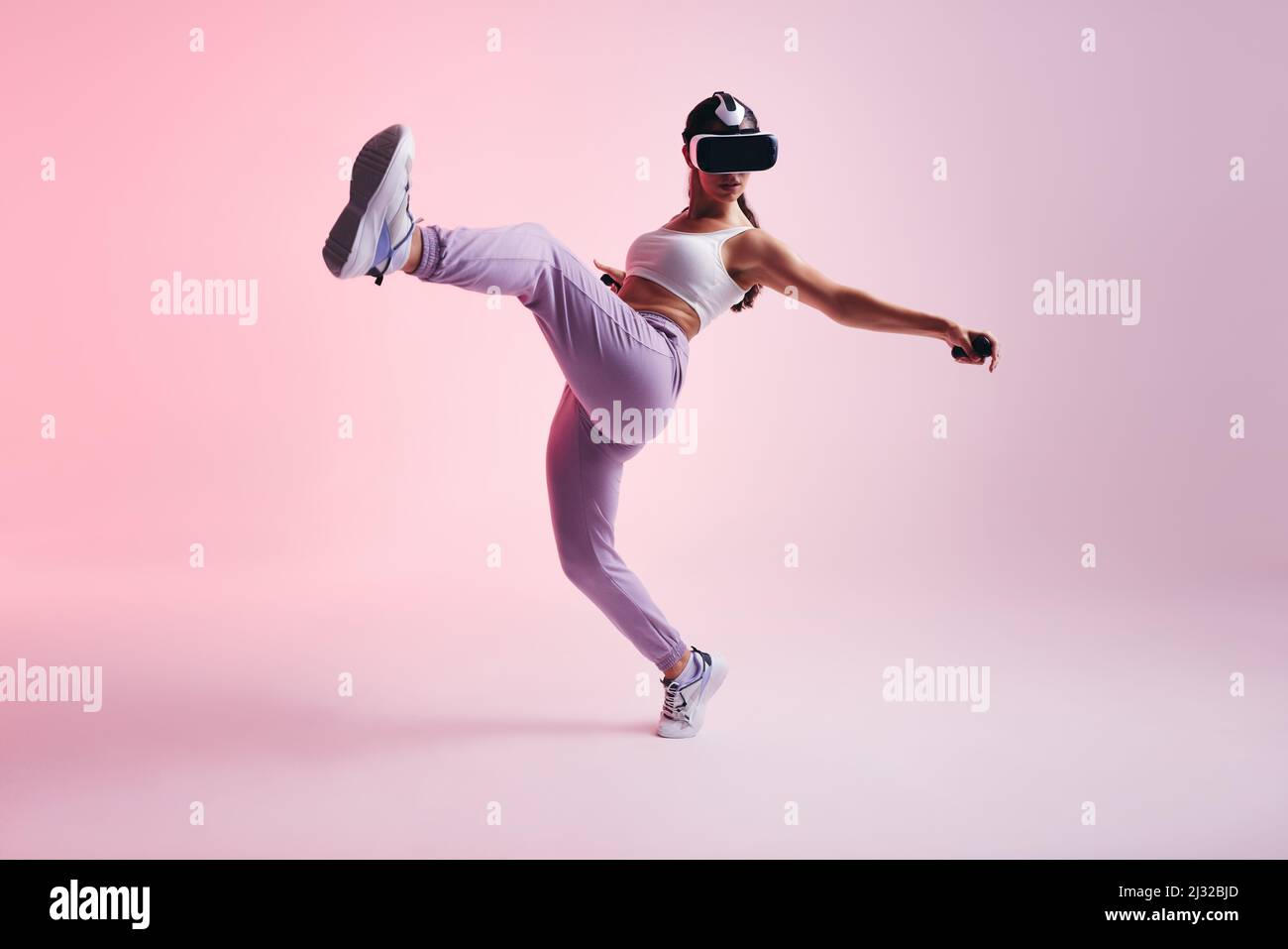 Active young woman throwing a kick in an immersive virtual reality game ...