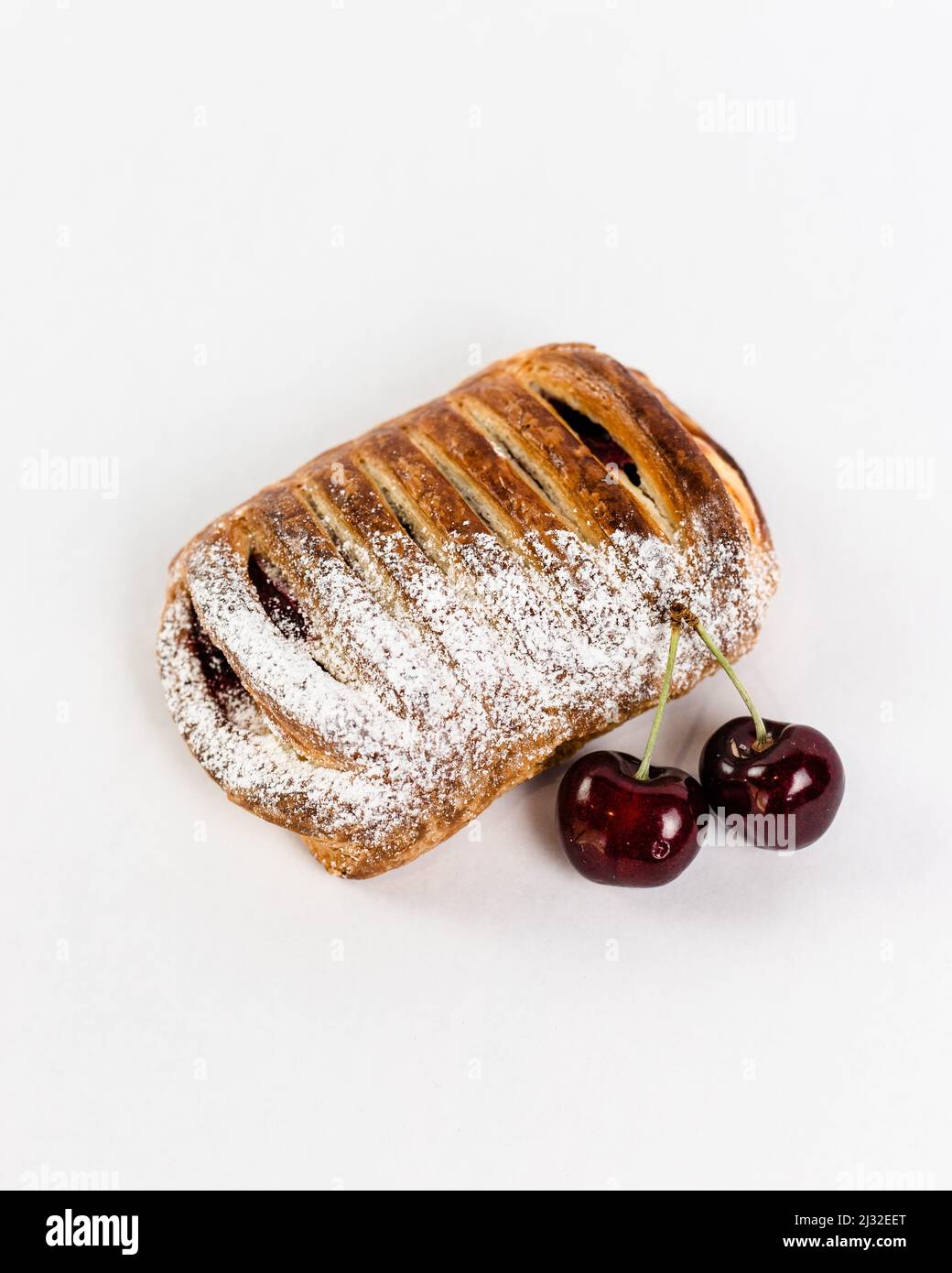 A Cherry Danish Dessert on a white background with Icing Sugar and ...