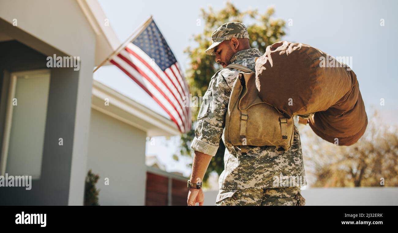 Rearview of a patriotic young soldier walking towards his house with ...