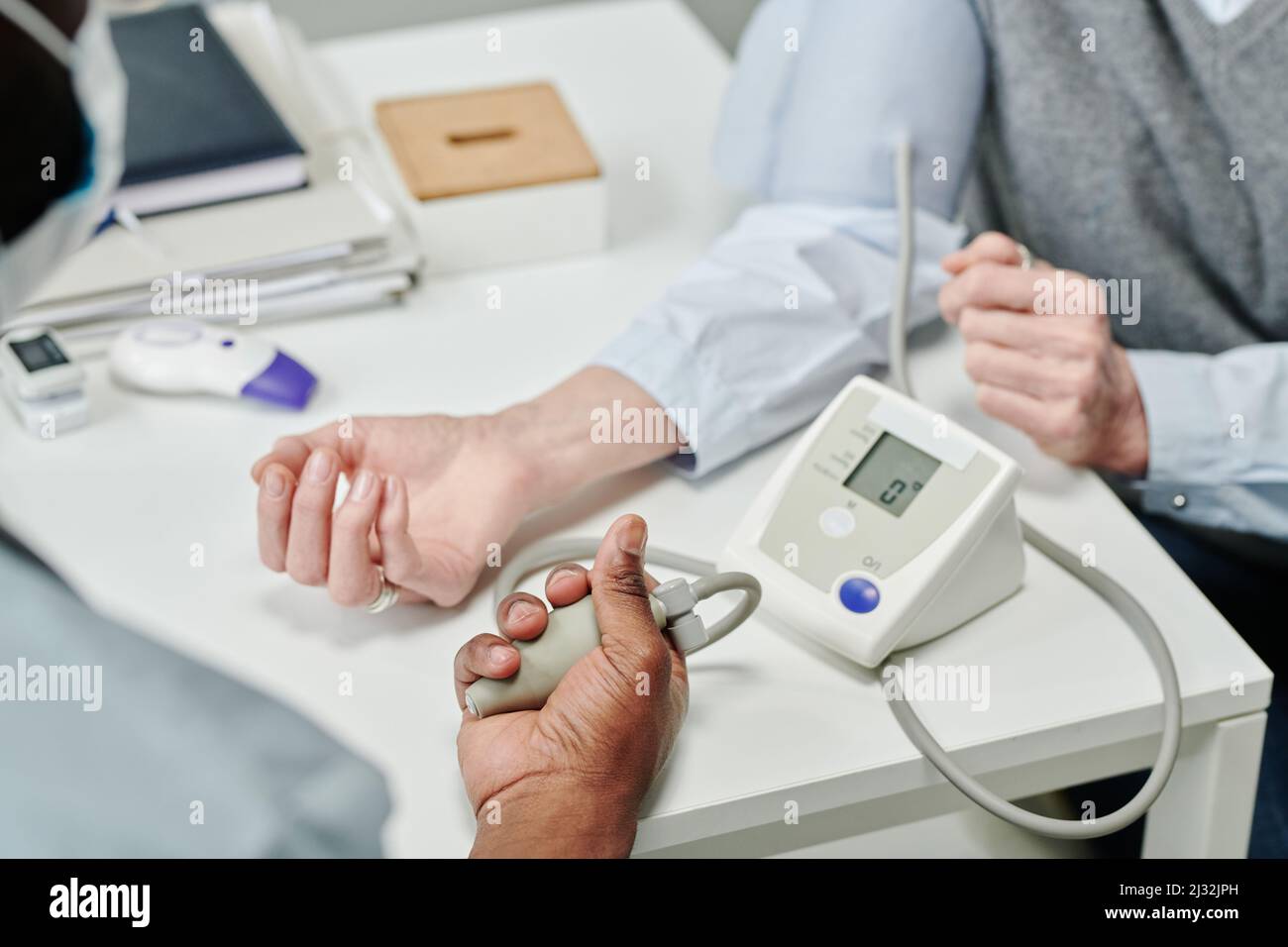 Hand of African American male physician pressing pump of tonometer ...