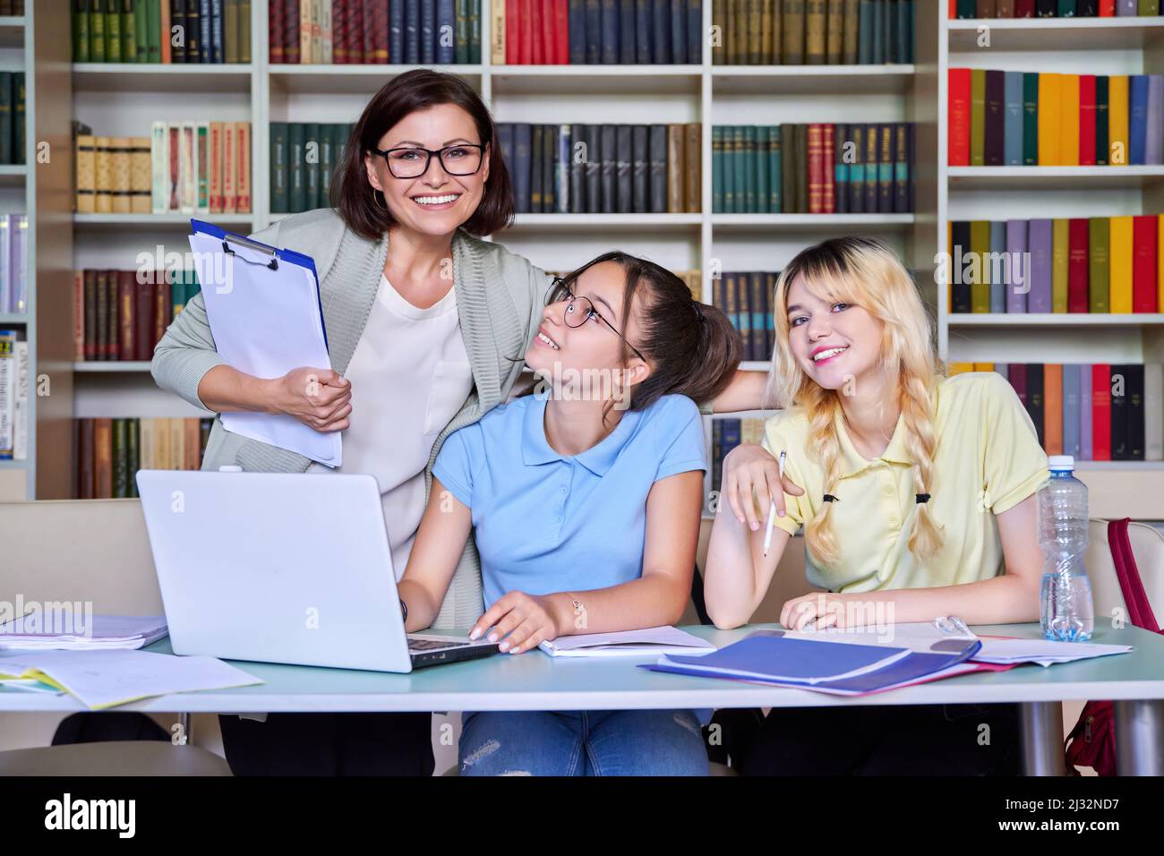 Girls teenage students studying in library with teacher mentor Stock ...