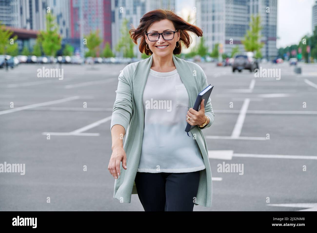 Smiling successful mature business woman walking outdoor, modern urban ... Smiling successful mature business woman walking outdoor, modern urban ...