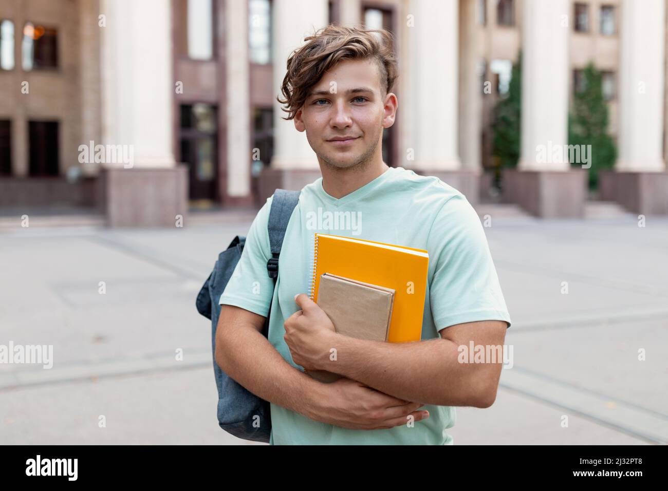 Portraif of happy student guy with backpack and workbooks posing over ...