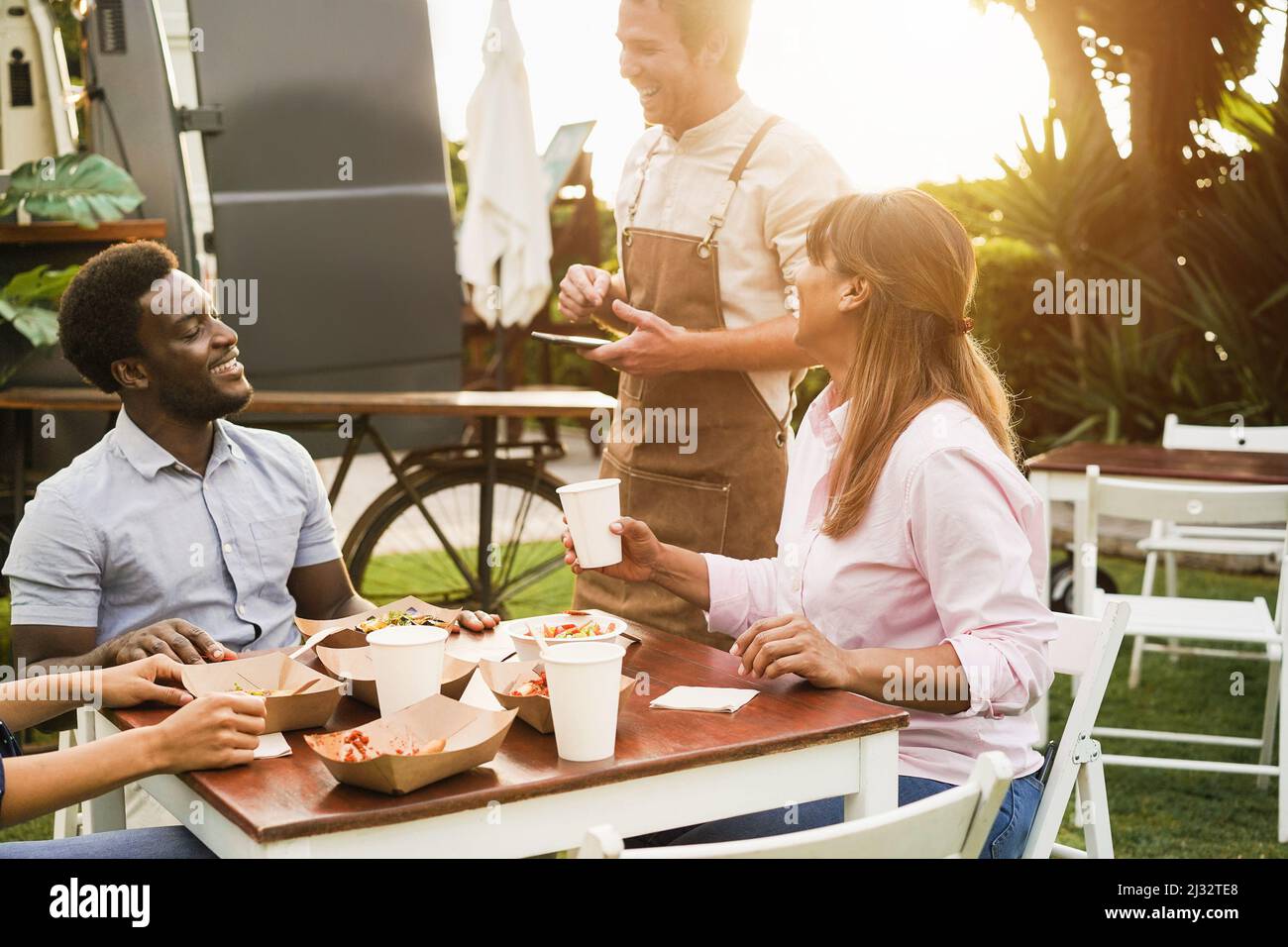 Multiracial people eating at food truck restaurant outdoor - Focus on ...
