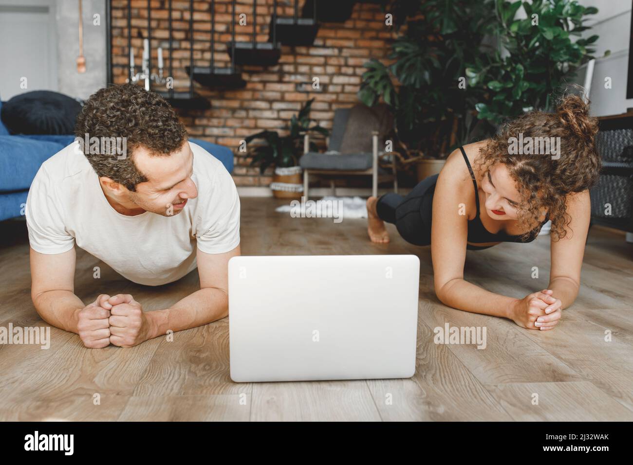 Young Caucasian sporty couple watching live or video tutorial practice ...