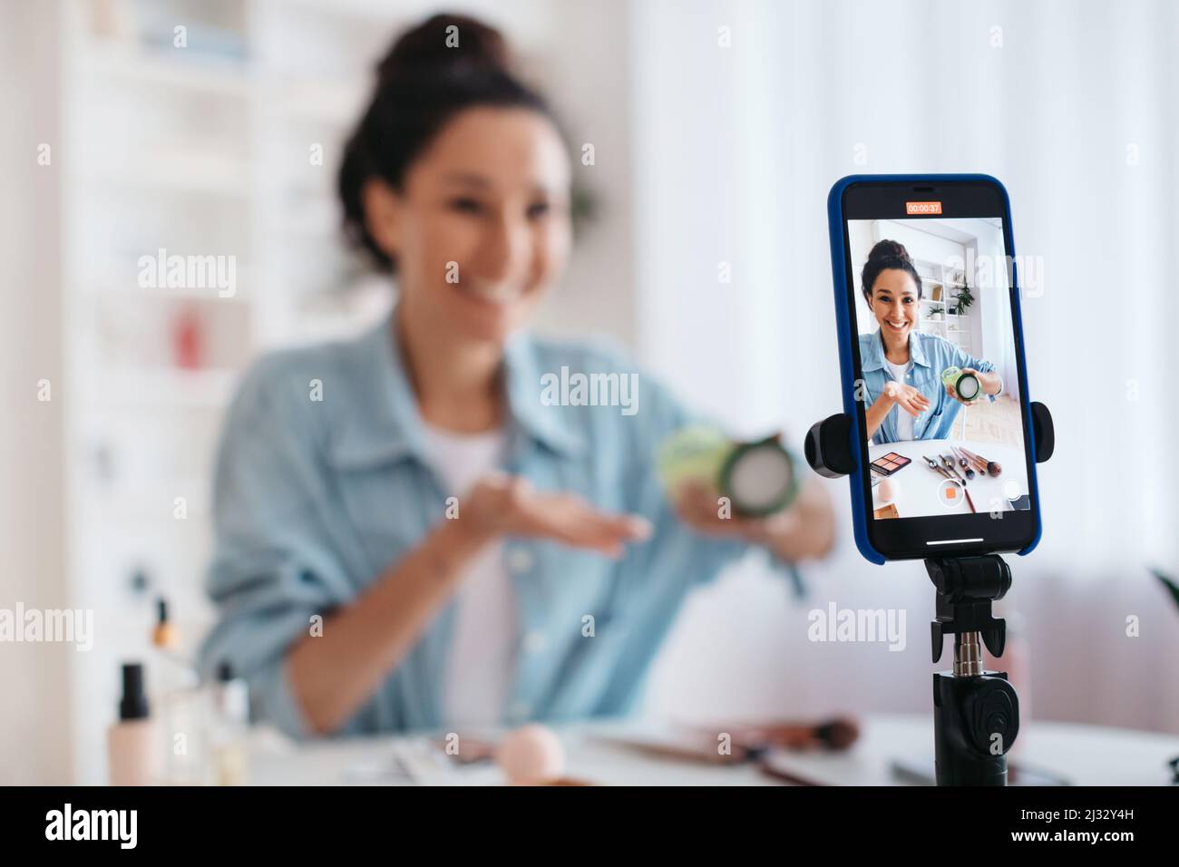 Female Blogger Using Phone Showing Makeup Product Making Video Indoors ...
