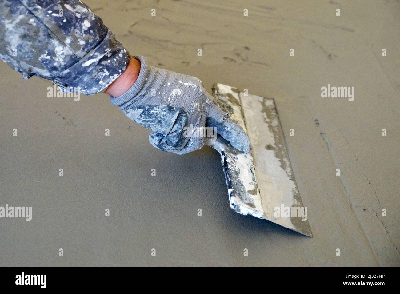 a man's hand with a spatula levels the cement screed on the floor Stock ...