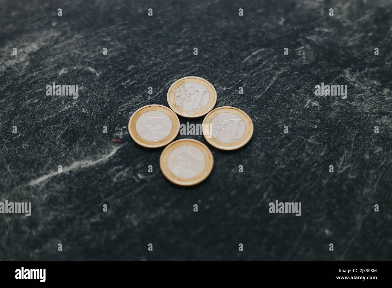 A closeup of 1 Euro coins on the dark textured surface Stock Photo - Alamy
