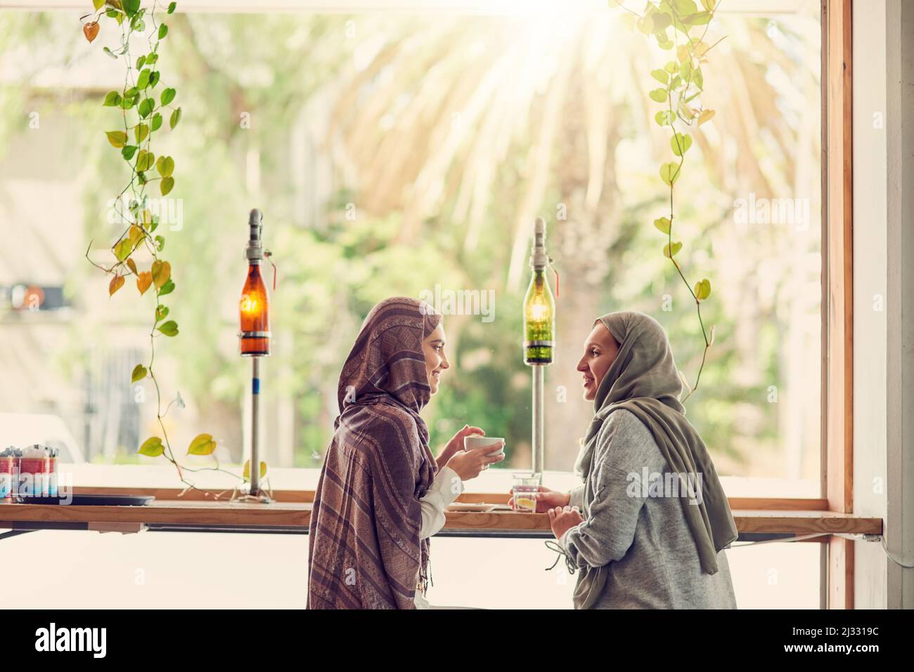 Getting their coffee and girl talk fix. Shot of two women chatting over ...