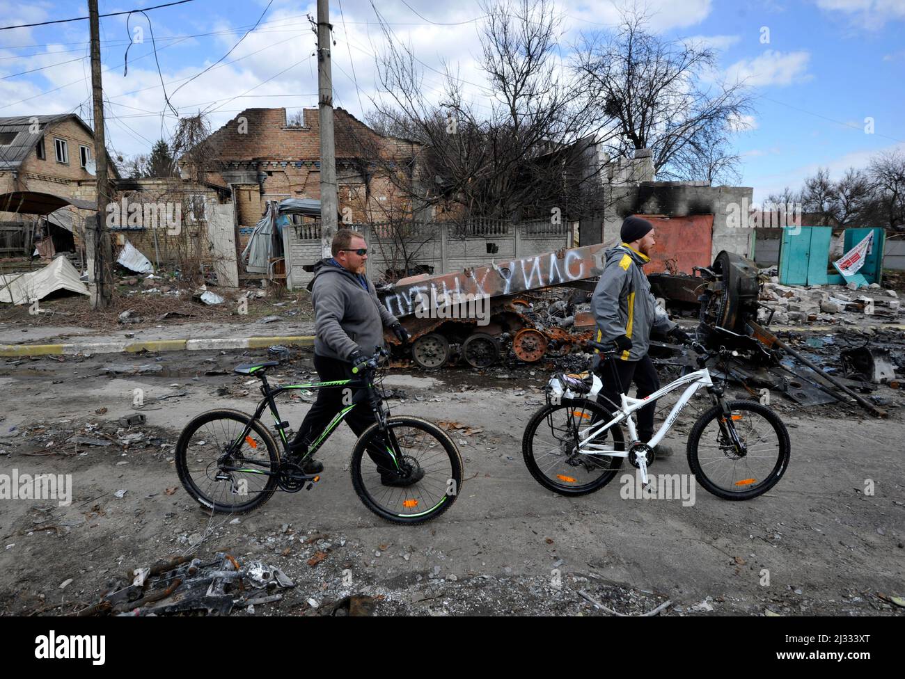 Men push their bikes past wrecked Russian military equipment in the ...