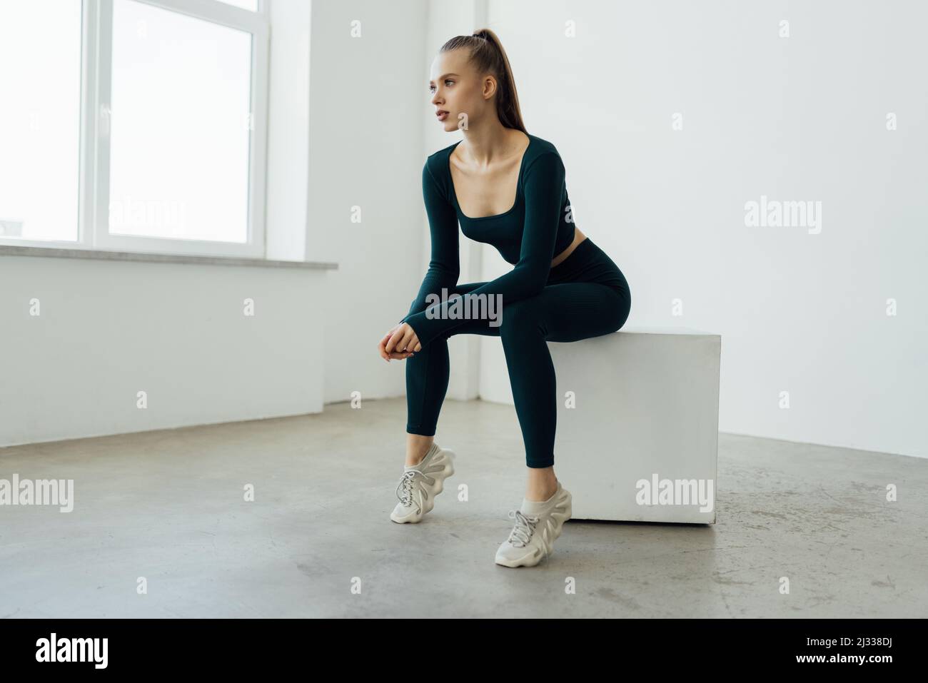 Fit young woman sitting on a box after exercising. Woman wearing sports ...