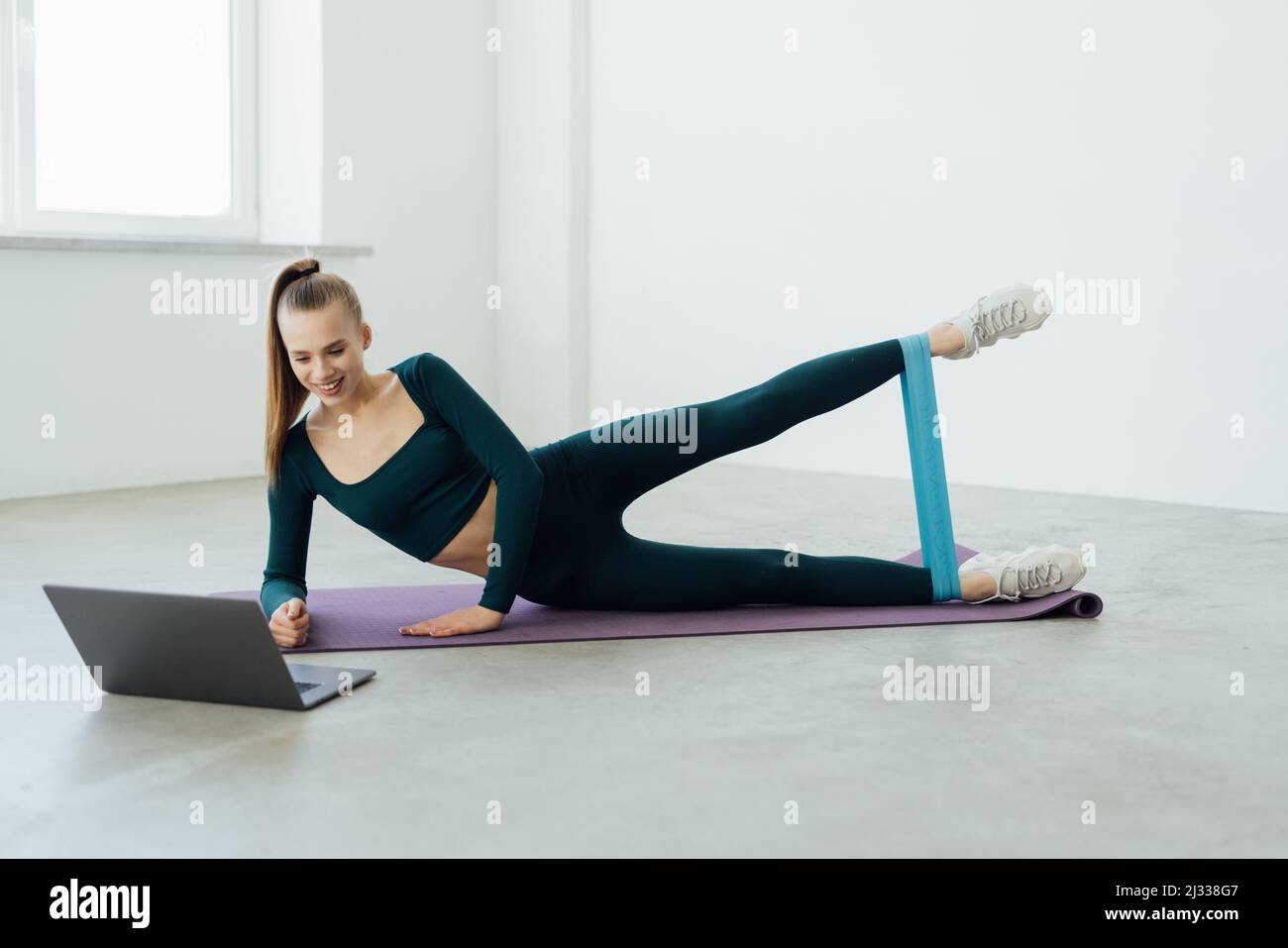 Active sporty beautiful girl watch laptop aerobics yoga workout stretch ...