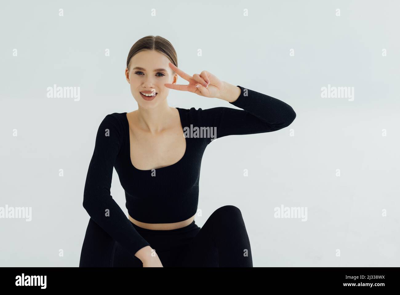 Young fit woman in sportswear with ponytail sitting on a floor over ...