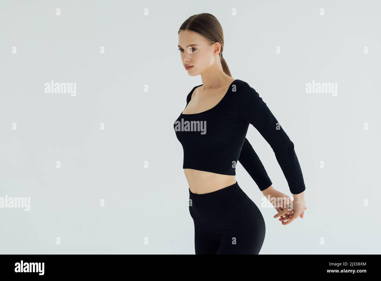 Side view portrait of a young fitness woman standing and stretching ...
