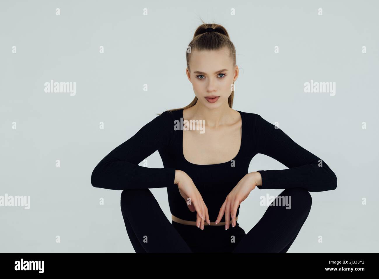 Young fit woman in sportswear with ponytail sitting on a floor over ...