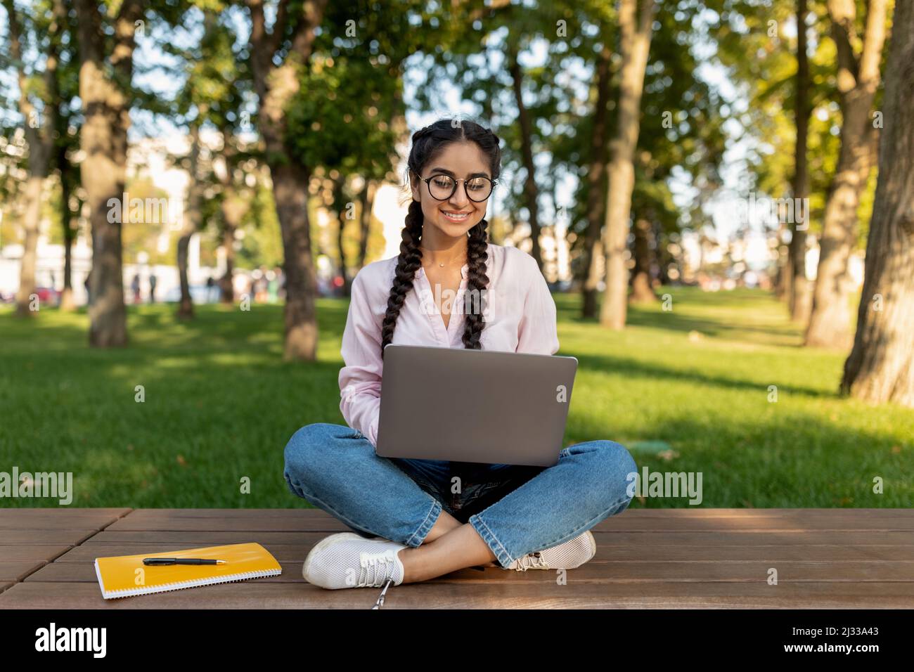 E-learning concept. Indian female student with laptop sitting on bench ...