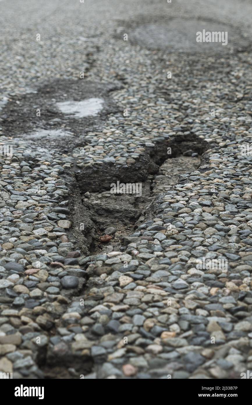 Pits in the asphalt road with stones. Destroyed road surface. Poor ...