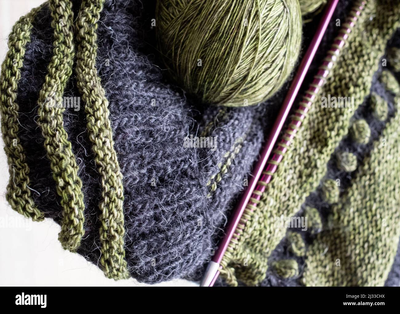 Green and grey wool sweater in process of being knitted. Photograph ...
