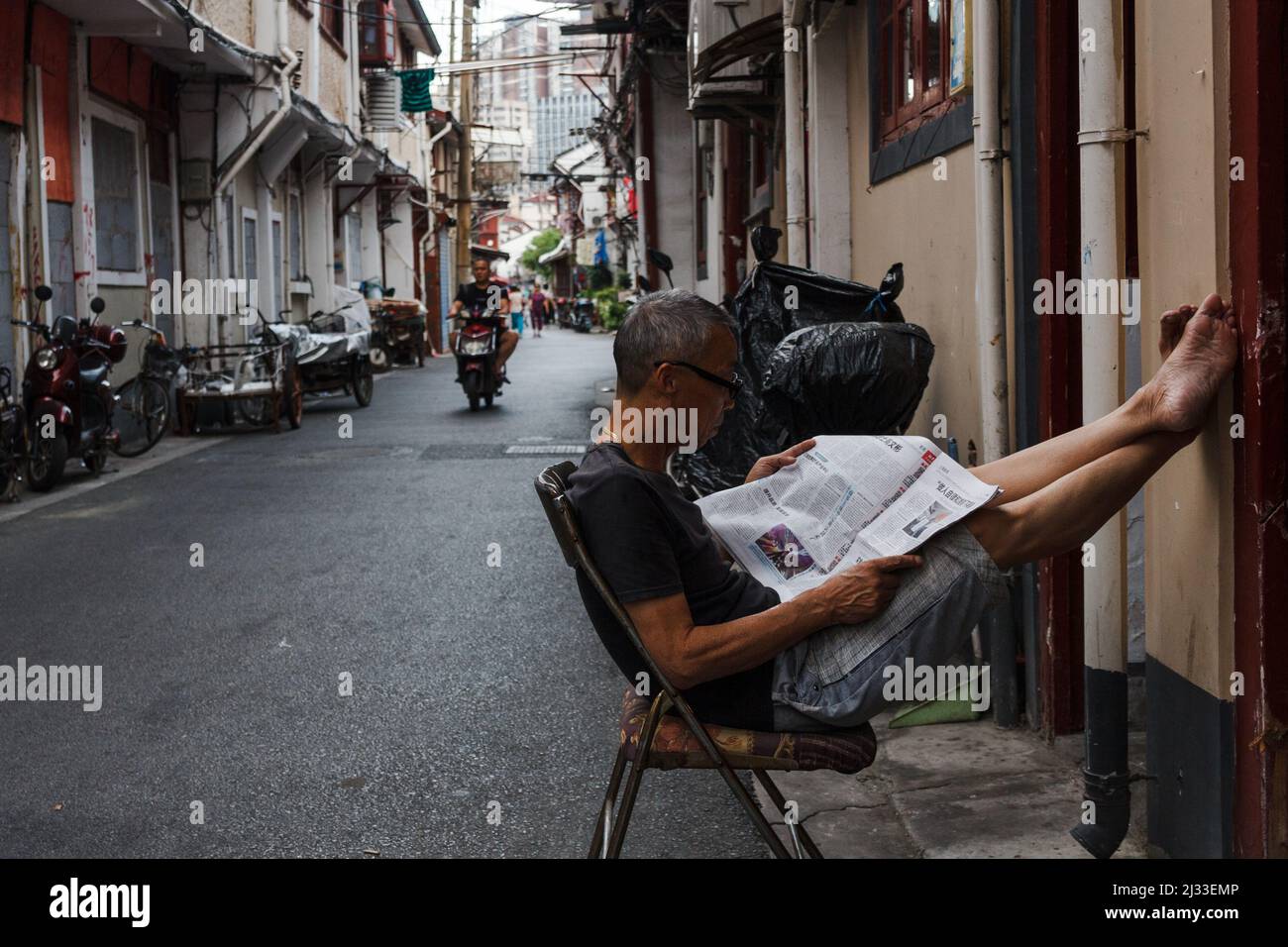 Shanghai, China- Man rests on a street in one of the oldest ...