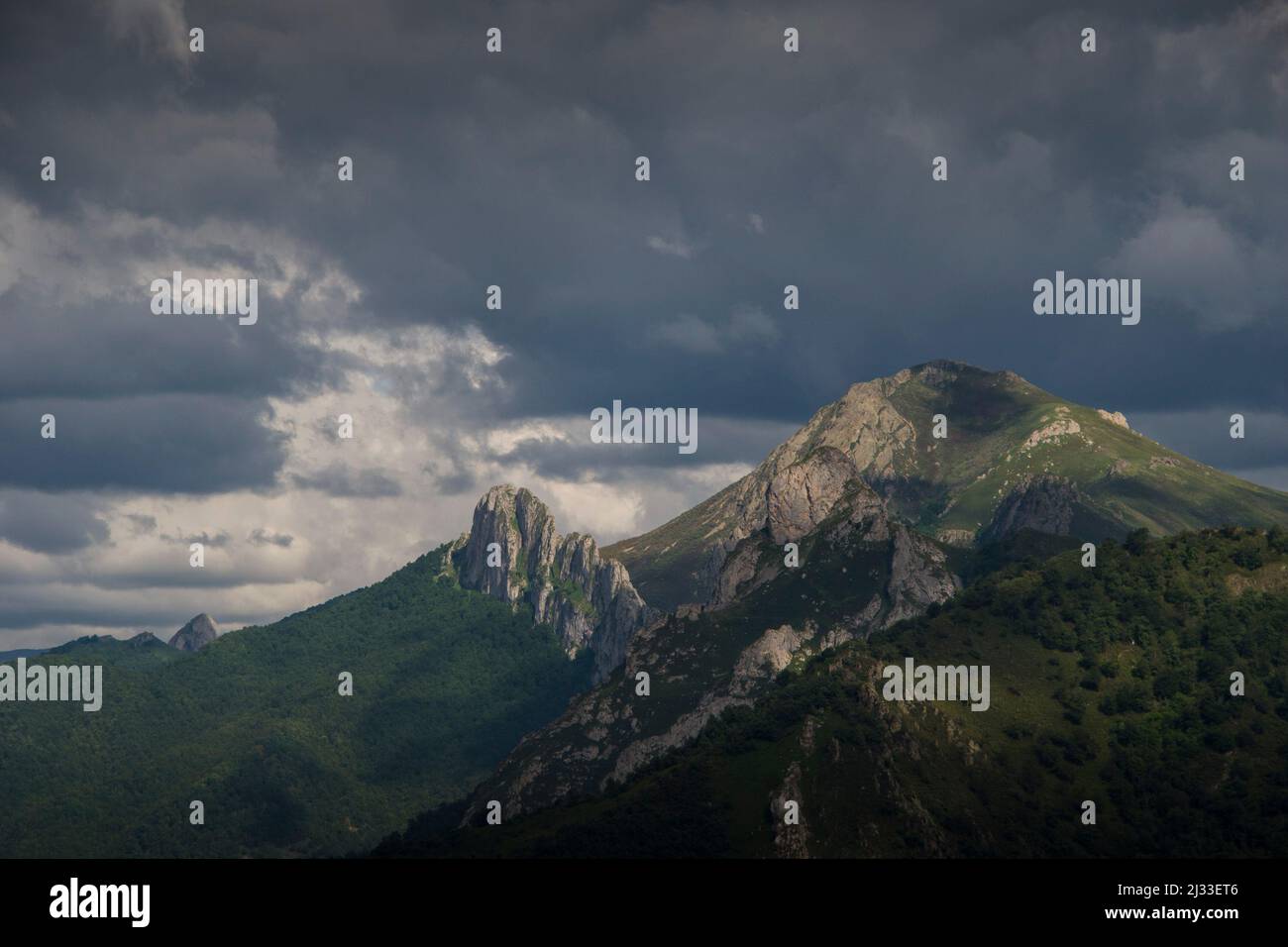 Stunning sun rays shine through a cloudy sky on edgy mountain peaks ...