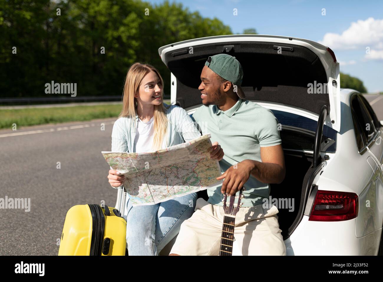 Affectionate black guy and his girlfriend studying map while sitting in ...