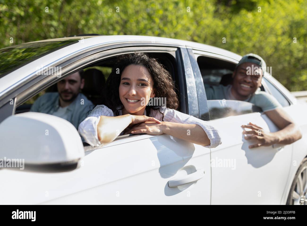 Multiracial young people riding auto, looking through windows, going on ...