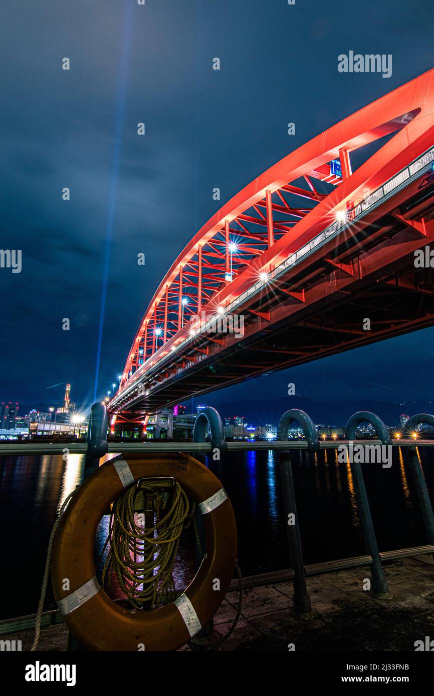 A vertical shot of the famous historic Kobe Bridge at night with city ...