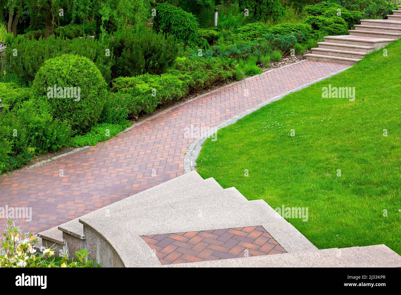 stone steps to a path from paving slabs in a park on a slope with ...
