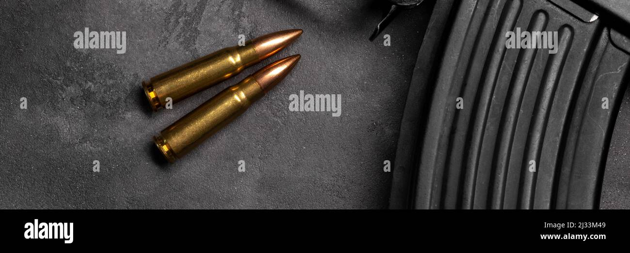 Two bullets and Kalashnikov assault rifle on gray concrete background ...