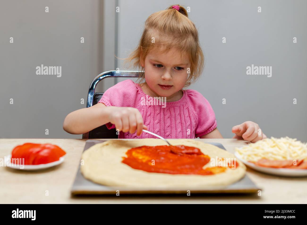 Little girl making pizza. Small child cooking meal in the kitchen at ...
