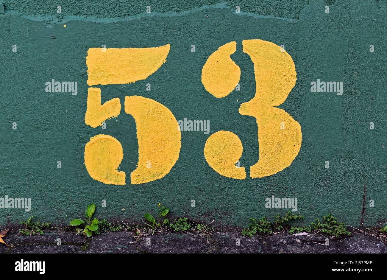 Number 53 painted in yellow on a green wall Stock Photo - Alamy