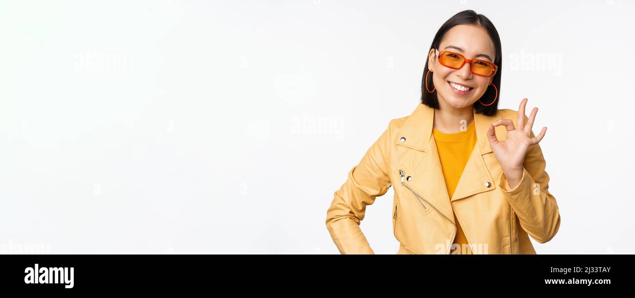Excellent. Smiling asian girl shows okay, ok sign, nod in approval ...