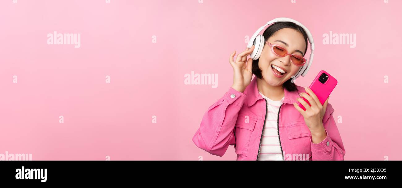 Stylish asian girl dancing with smartphone, listening music in ...