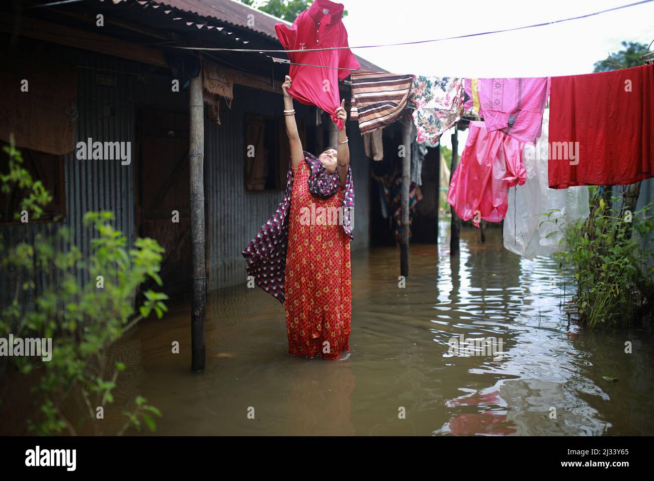 A woman dries clothes inside her flooded home in Sunamganj, in north ...
