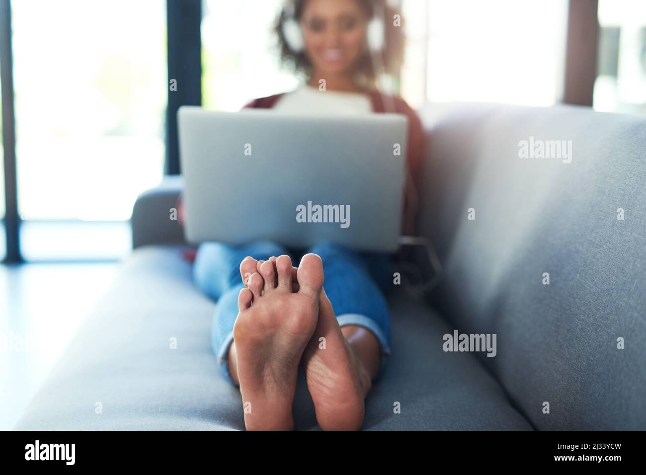 Relaxed feet are happy feet. Shot of a young woman using headphones and ...