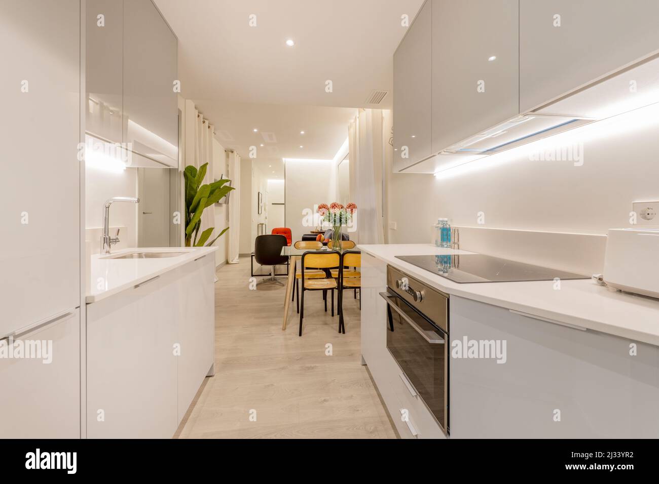 Walk-through kitchen with white cabinets and built-in appliances ...