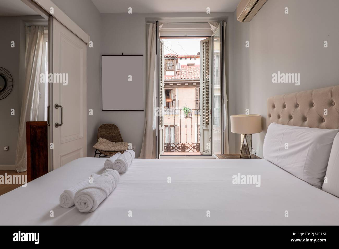 Bedroom with double bed, capitone upholstered fabric headboard, balcony ...