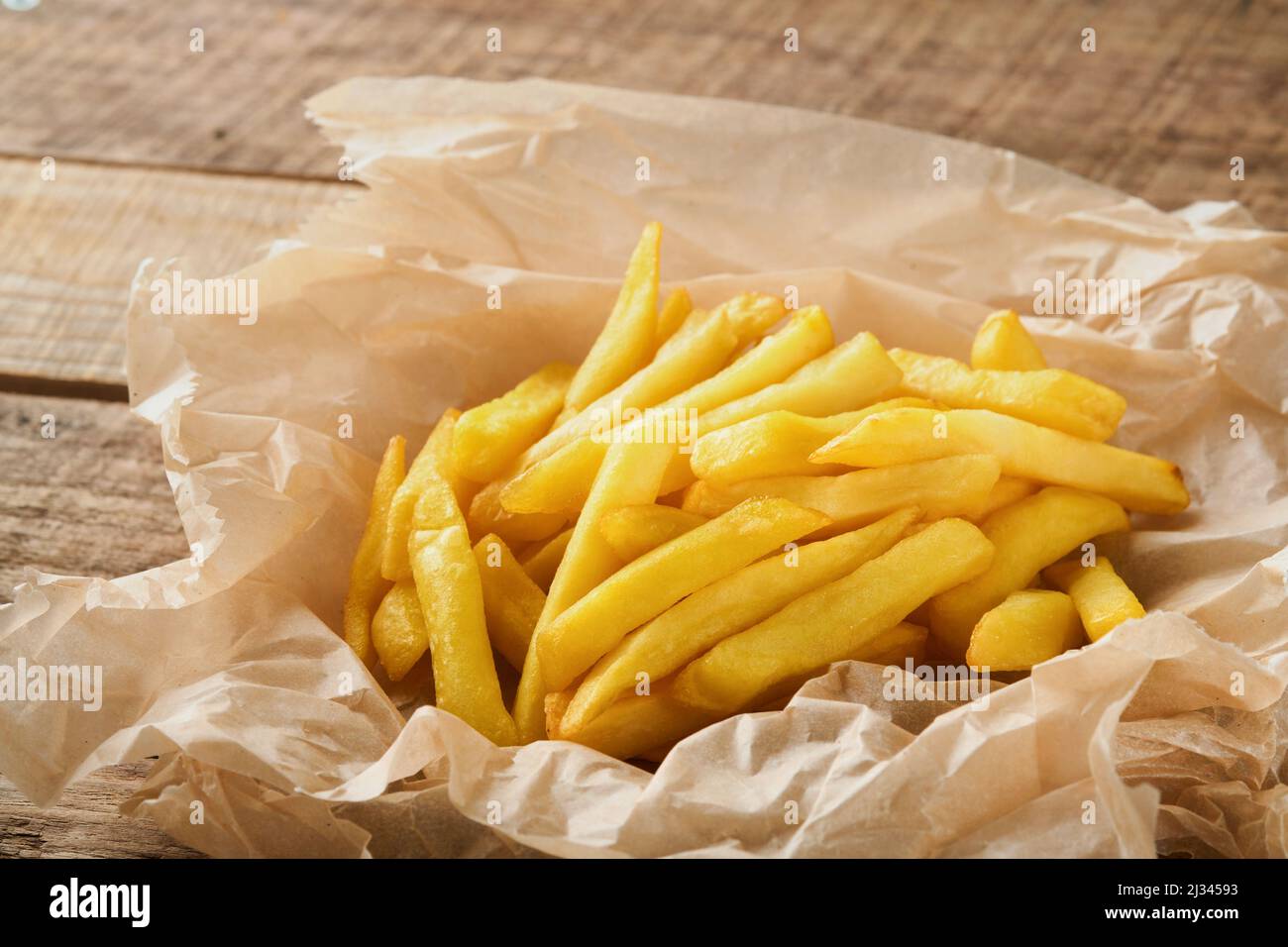 French fries. Tasty French fries server on parchment paper on wooden ...