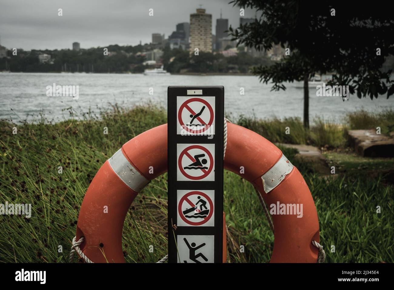 A shallow focus shot of a stone lifebuoy with banner on it with warning ...
