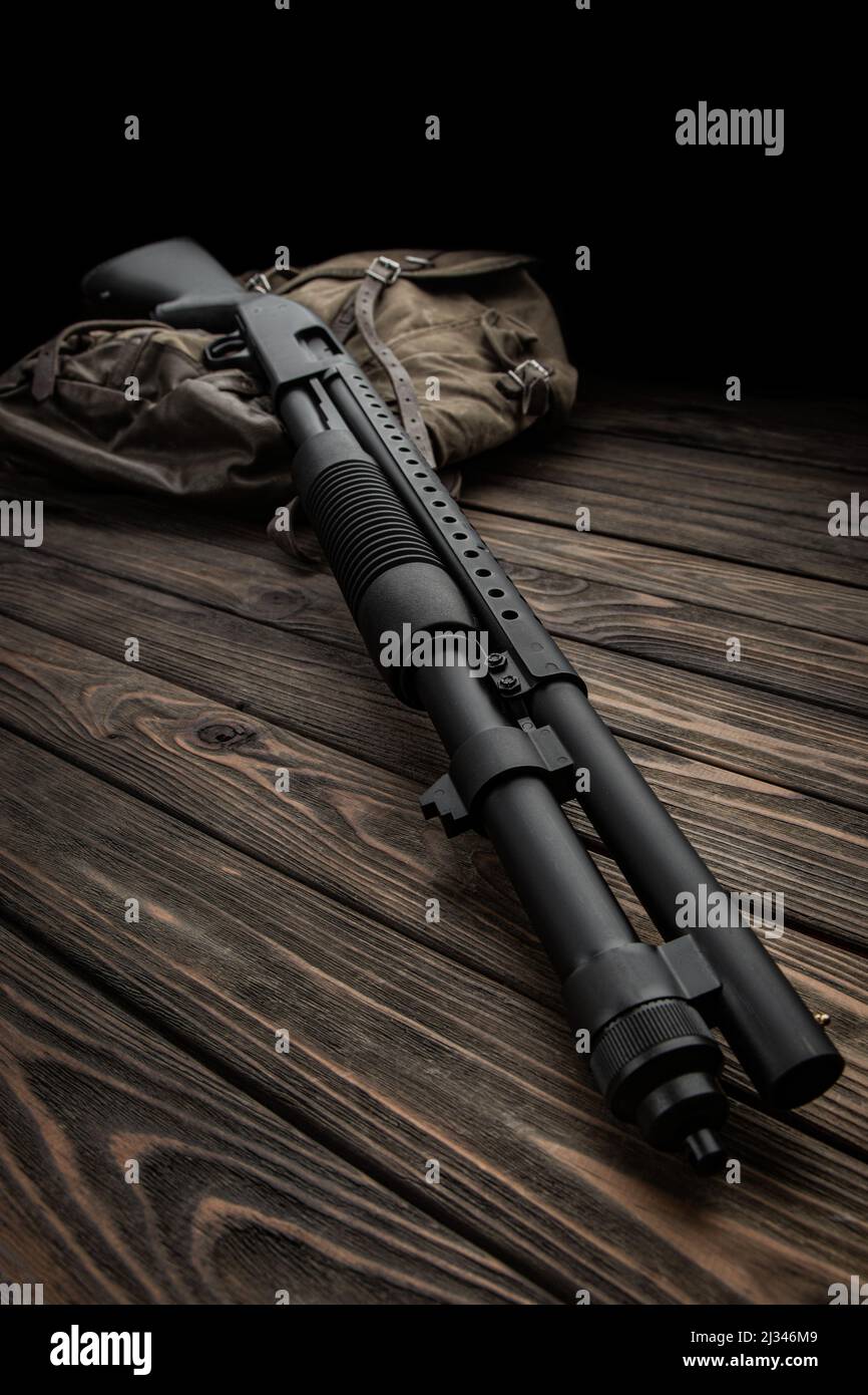 A black 12-gauge pump-action shotgun and ammo are on a canvas backpack ...