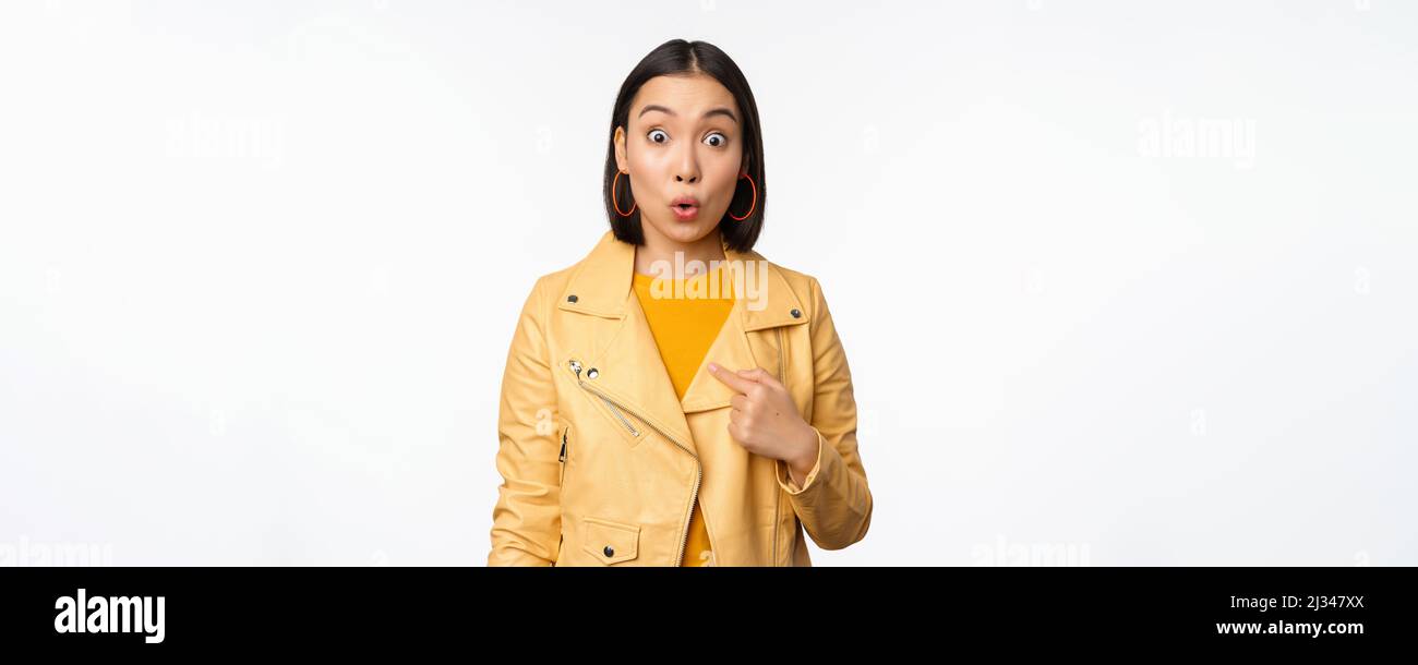 Portrait of asian girl looks surprised, points at herself with ...