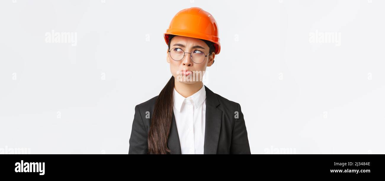 Close-up of gloomy upset asian female engineer in safety helmet and ...